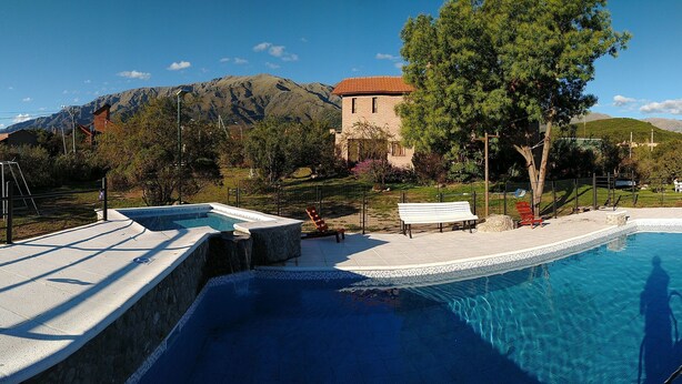 Uma piscina com deck de pedra, um banco e vista para montanhas ao fundo.