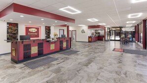 Uma área de recepção de hotel com chão de mármore, um balcão de atendimento e um relógio na parede.
