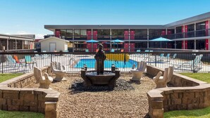 Um pátio com uma fonte, áreas de estar e uma piscina.