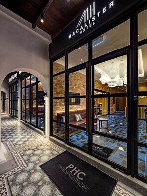 Entrada do Hotel Macalis com parede de tijolos por dentro e piso estampado.