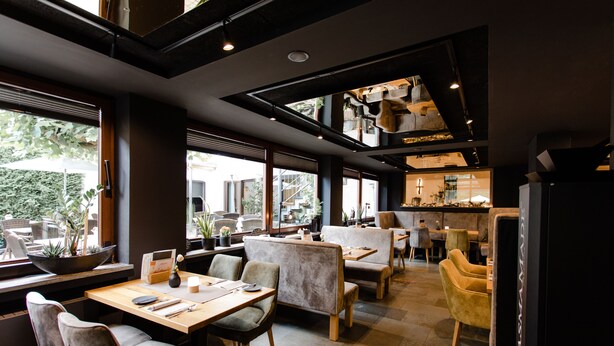 Restaurante com pé-direito alto, mobiliário moderno e grandes janelas.