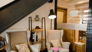 Uma sala de estar moderna com dois poltronas, uma mesa de centro, uma estante e uma escada.