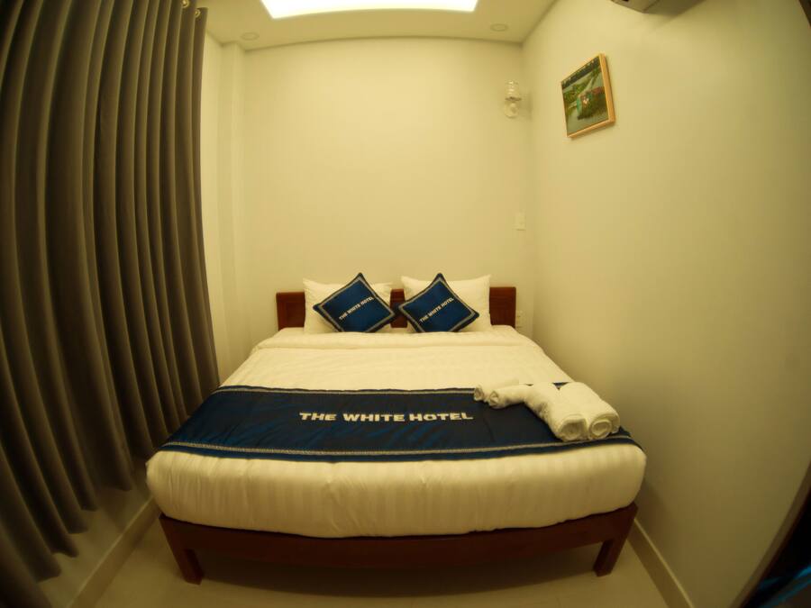 Quarto de hotel com cama, cortinas, um quadro na parede e uma toalha na cama.