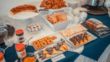 Mesa de buffet com diversos alimentos, incluindo doces, bolachas e uma variedade de patês.