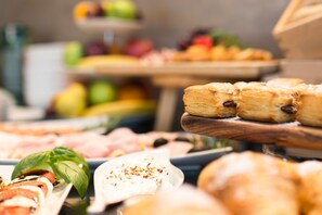 Buffet com diversos itens de comida, incluindo doces, carnes e legumes.