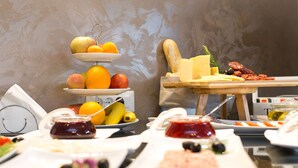 Buffet de café da manhã com diversas frutas, queijos e patês.