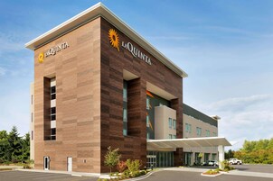 Um hotel La Quinta com design moderno, apresentando uma entrada imponente e área de estacionamento.