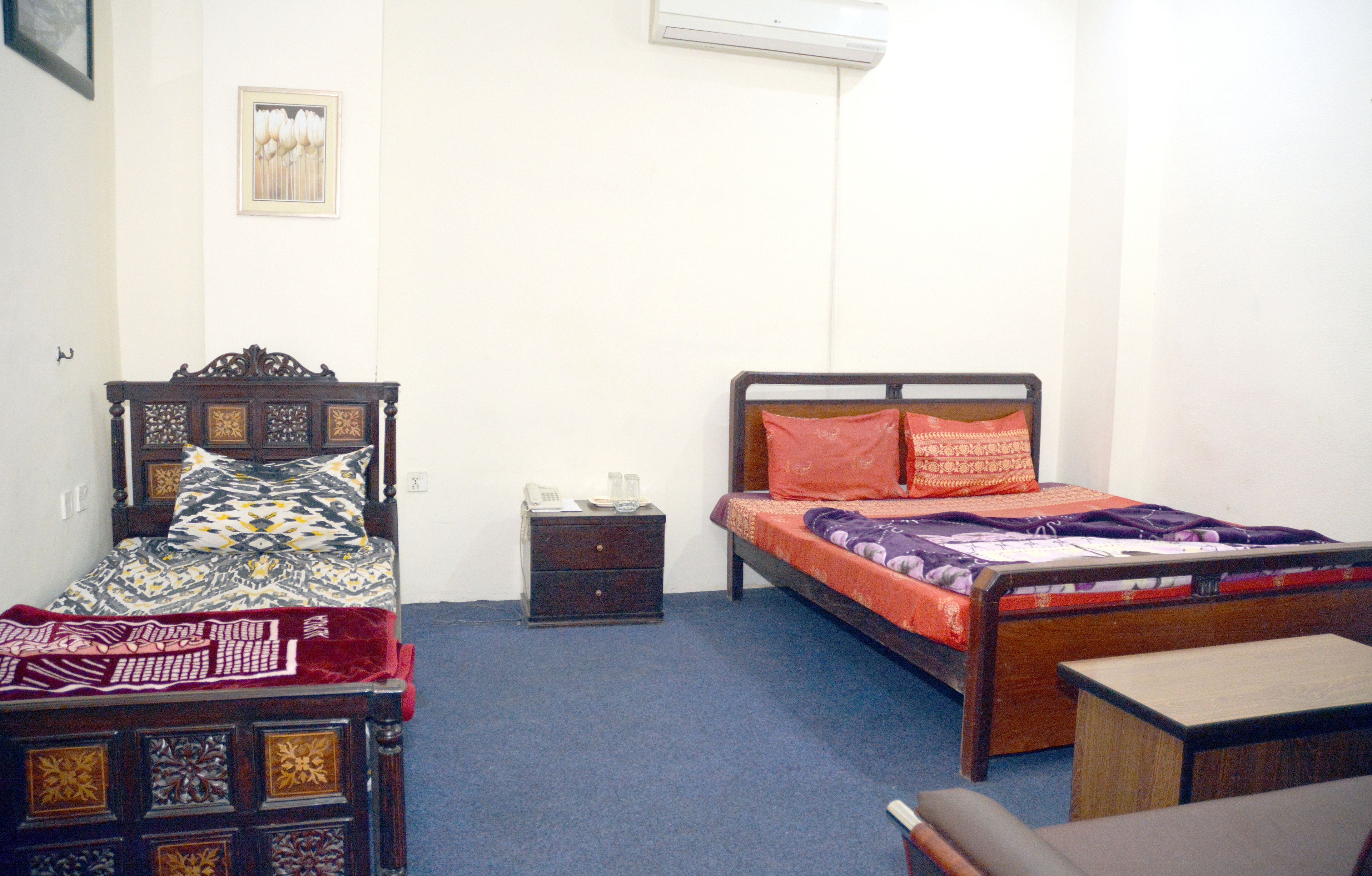 Quarto com duas camas de madeira, uma mesa de cabeceira, uma escrivaninha e uma cadeira.