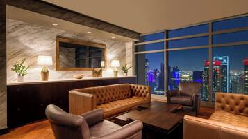Uma sala de estar moderna com vista para a cidade, com um sofá, poltronas, uma mesa de centro e uma parede de destaque em mármore.
