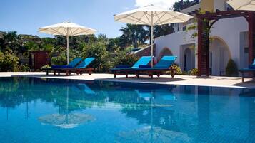 Uma área de piscina com espreguiçadeiras e guarda-sóis.