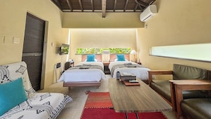 Quarto com duas camas, um sofá, uma mesa e uma televisão.
