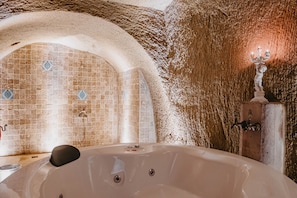 Um salão de spa com uma banheira grande, paredes azulejadas e uma fonte decorativa.