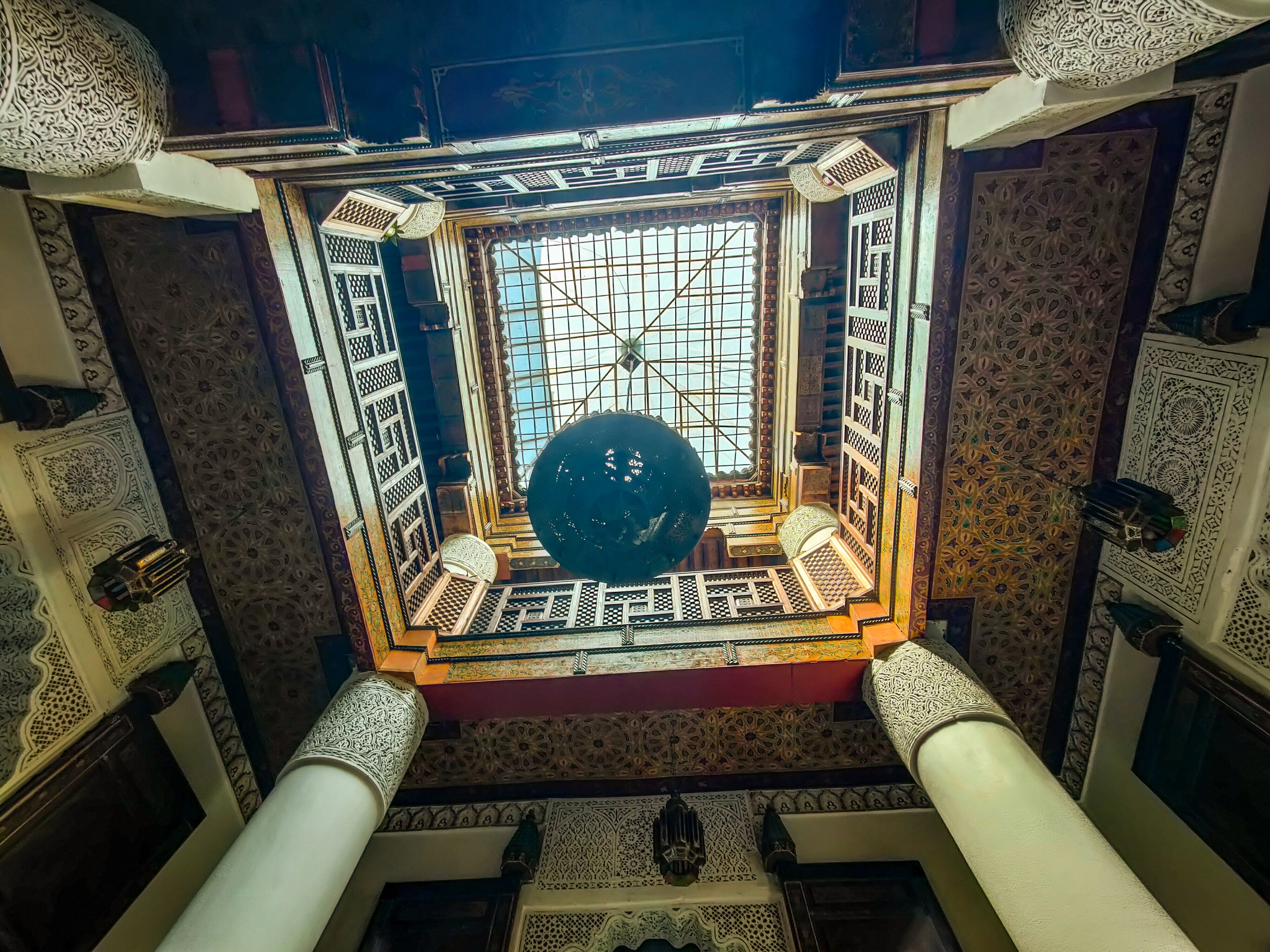 Um quarto com pé-direito alto, detalhes intrincados em azulejos e um objeto esférico grande no centro.