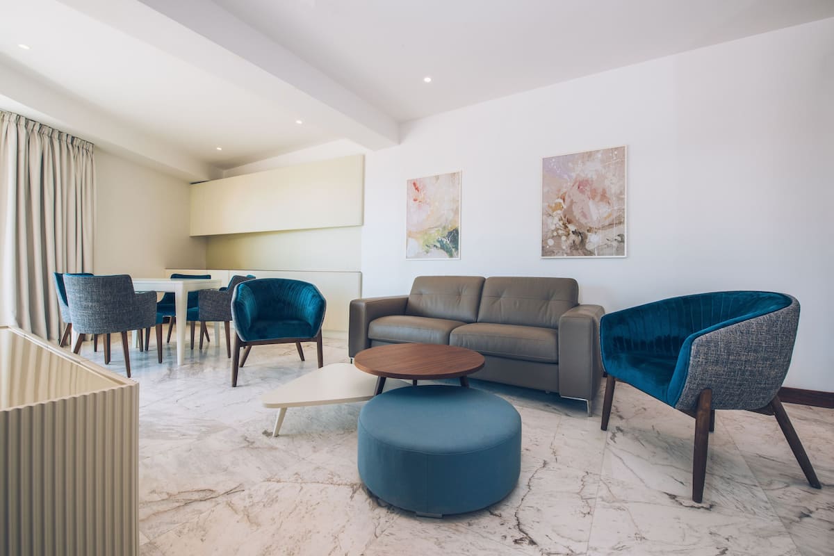 Uma sala de estar moderna com sofá, cadeiras, mesa de centro e obras de arte nas paredes.