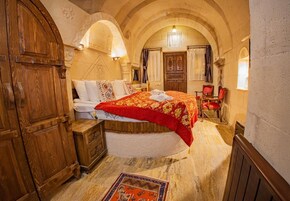 Quarto tradicional com cama, móveis de madeira e paredes de pedra.