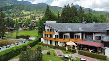 Hotel com um pátio, área de estar ao ar livre e montanhas ao fundo.