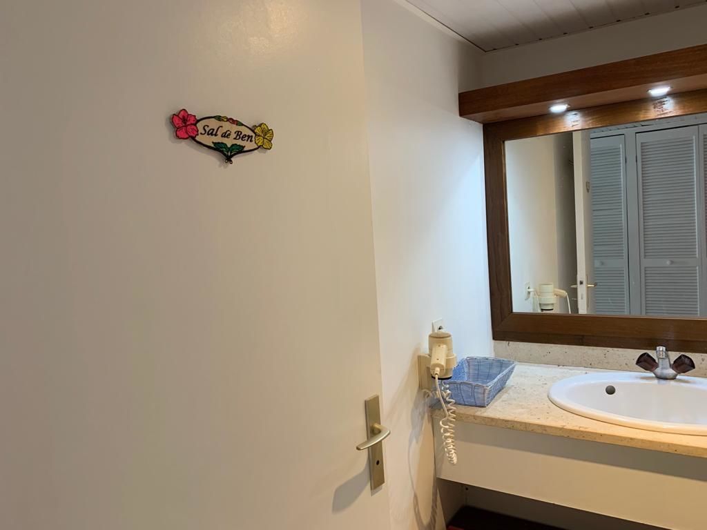 Uma casa de banho com uma pia, espelho e um letreiro decorativo na parede.