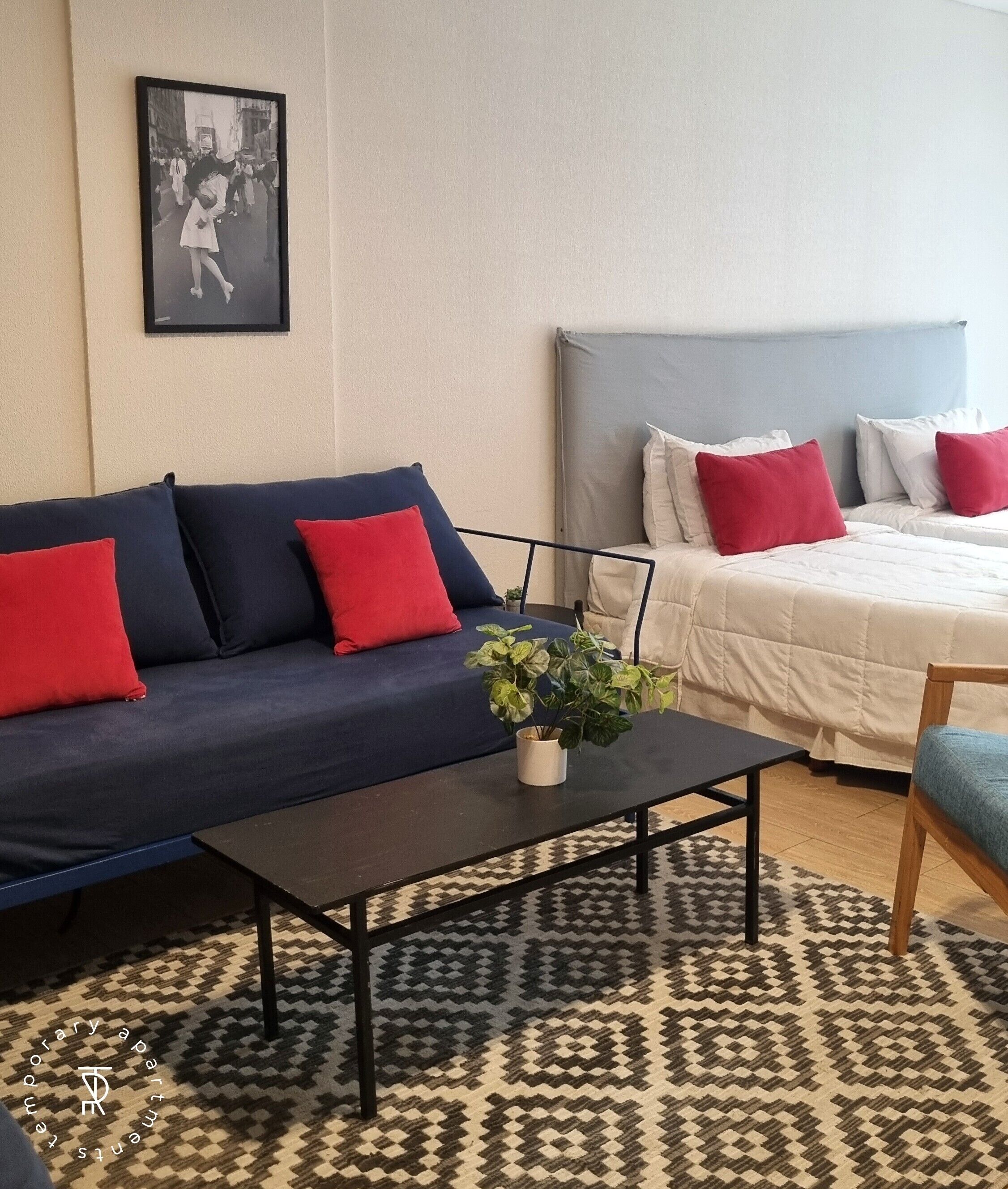 Quarto com sofá, cama, mesa pequena e quadro na parede.