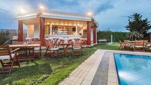 Uma área de bar ao ar livre coberta, com assentos e piscina.