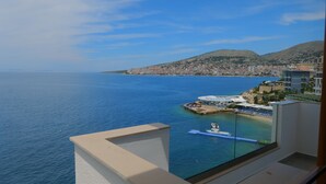 Paisagem costeira com vista clara para o mar, um pequeno barco atracado perto da costa e um edifício com uma placa que diz 'Beach Bar & Restaurant'.