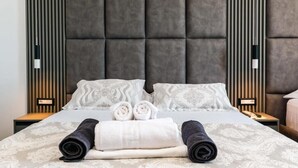 Cama bem arrumada com toalhas dobradas e cabeceira com ripas verticais.