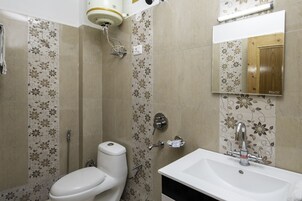 Casa de banho com sanita, chuveiro e lavatório.