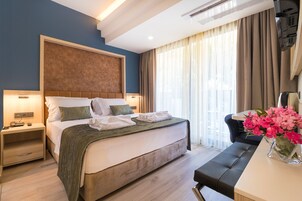 Quarto de hotel com uma cama grande, mesas de cabeceira, escrivaninha e uma cadeira.