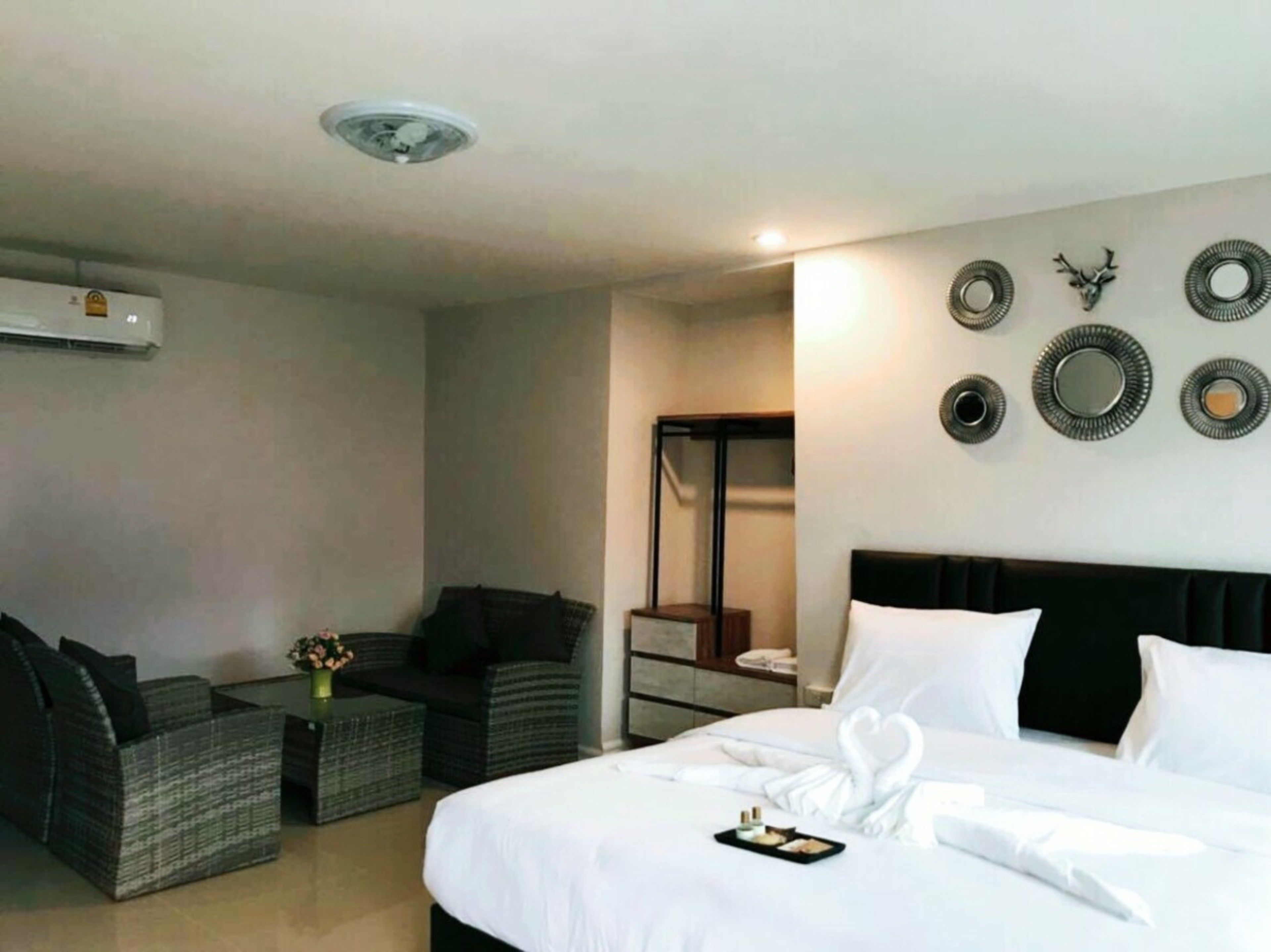 Quarto de hotel com uma cama, um pequeno espaço de estar com uma mesa e um espelho.