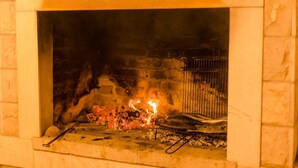 Lareira com grade de metal e fogo aceso.