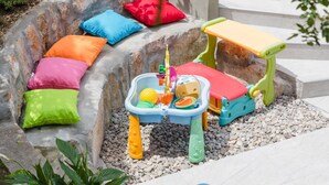 Uma área de estar ao ar livre e colorida, com uma pequena mesa e almofadas.