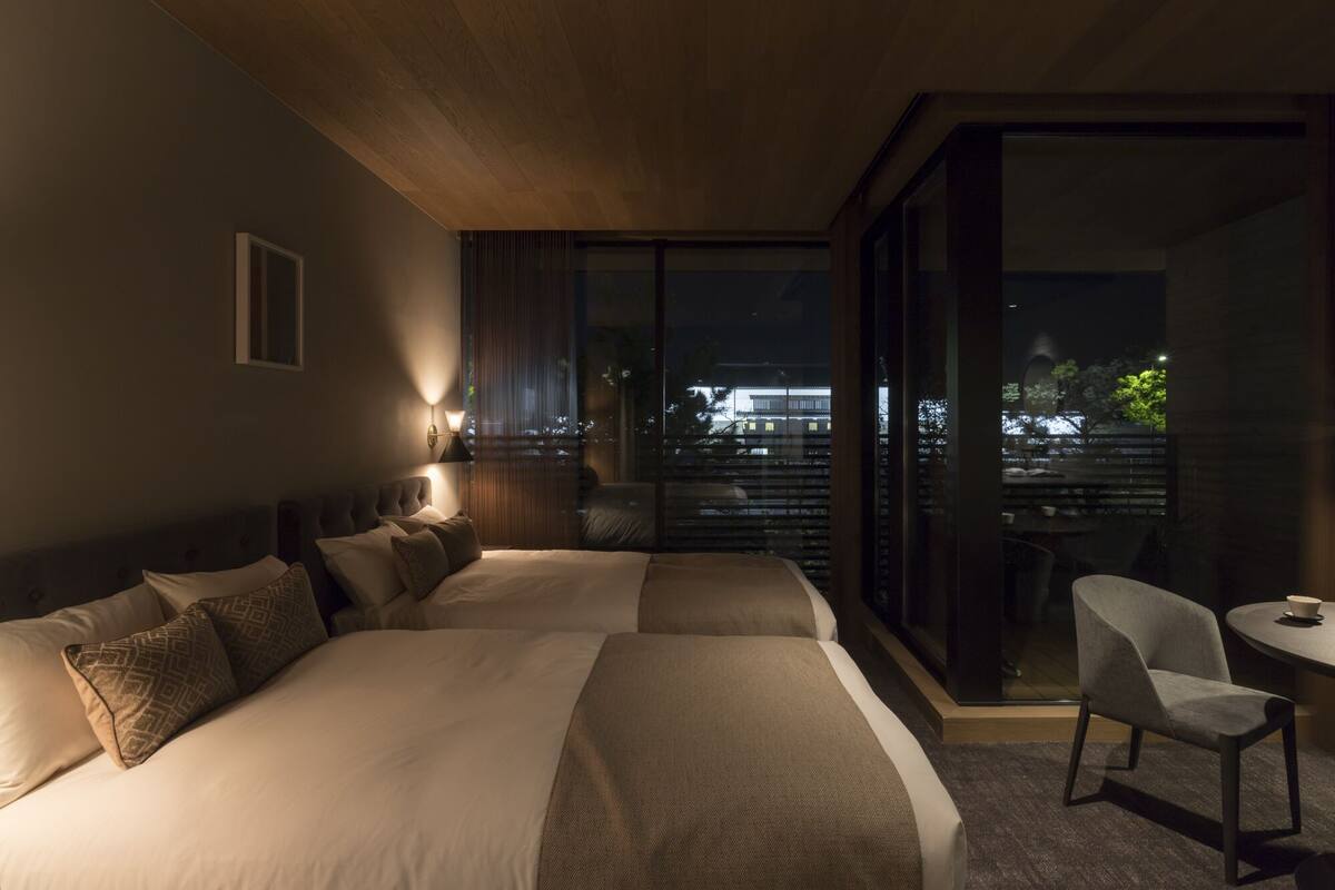 Quarto de hotel com duas camas, uma escrivaninha e uma cadeira.