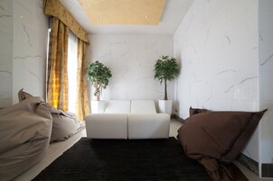 Quarto de hotel moderno com sofá, cama e duas plantas em vasos.