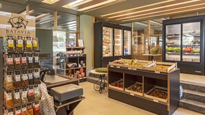 Interior de loja com prateleiras de especiarias, uma seção refrigerada e uma exposição de produtos frescos.