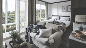 Quarto com uma grande janela, cama, sofá e um espaço de cozinha.
