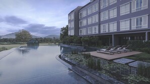Um edifício moderno com piscina, um deck de madeira com espreguiçadeiras e vista para montanhas.