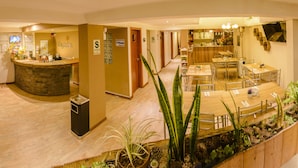 Um saguão de hotel com balcão de recepção, área de estar e exposição de artesanato.