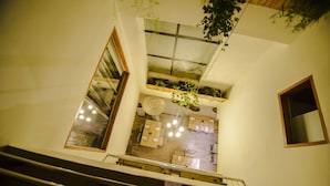 Vista aérea de um hall de hotel com escada, balcão de recepção e área de estar.