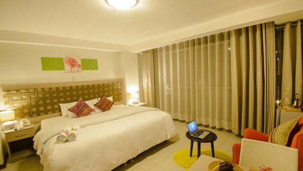 Quarto de hotel com duas camas, um laptop sobre uma mesinha e um espaço de refeições com uma cadeira e mesa.