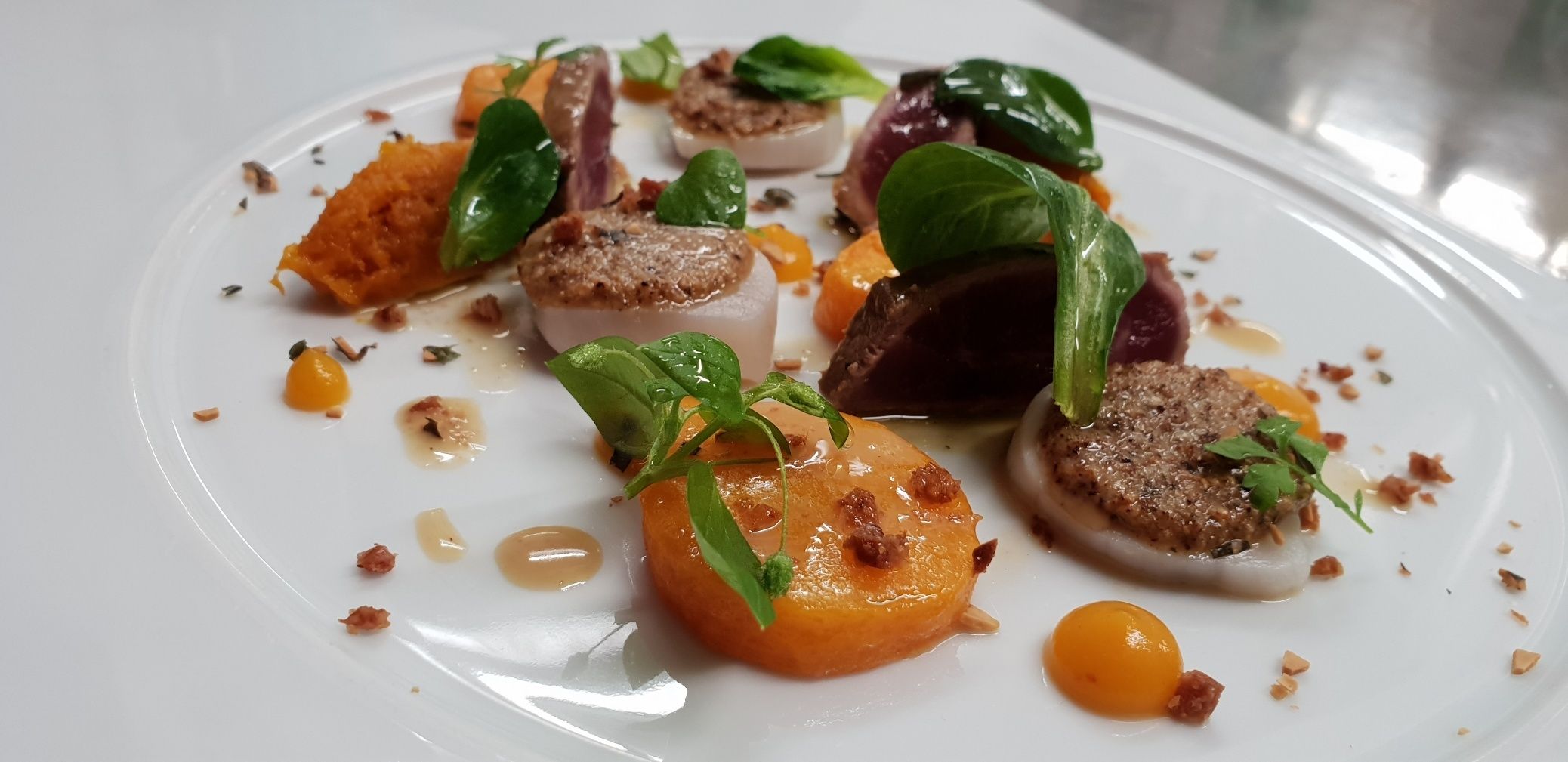 Um prato branco com diversos alimentos, incluindo fatias de carne, legumes e guarnições.