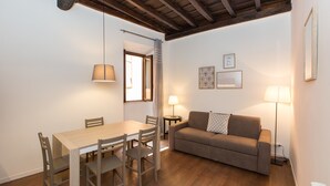 Uma sala de estar aconchegante com uma mesa de jantar de madeira, cadeiras, um sofá e um abajur.