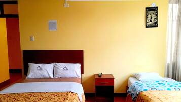 Quarto de hotel com duas camas, uma mesinha de cabeceira e um cartaz na parede.