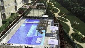 Piscina no terraço com espreguiçadeiras, cercada por uma grade e palmeiras.