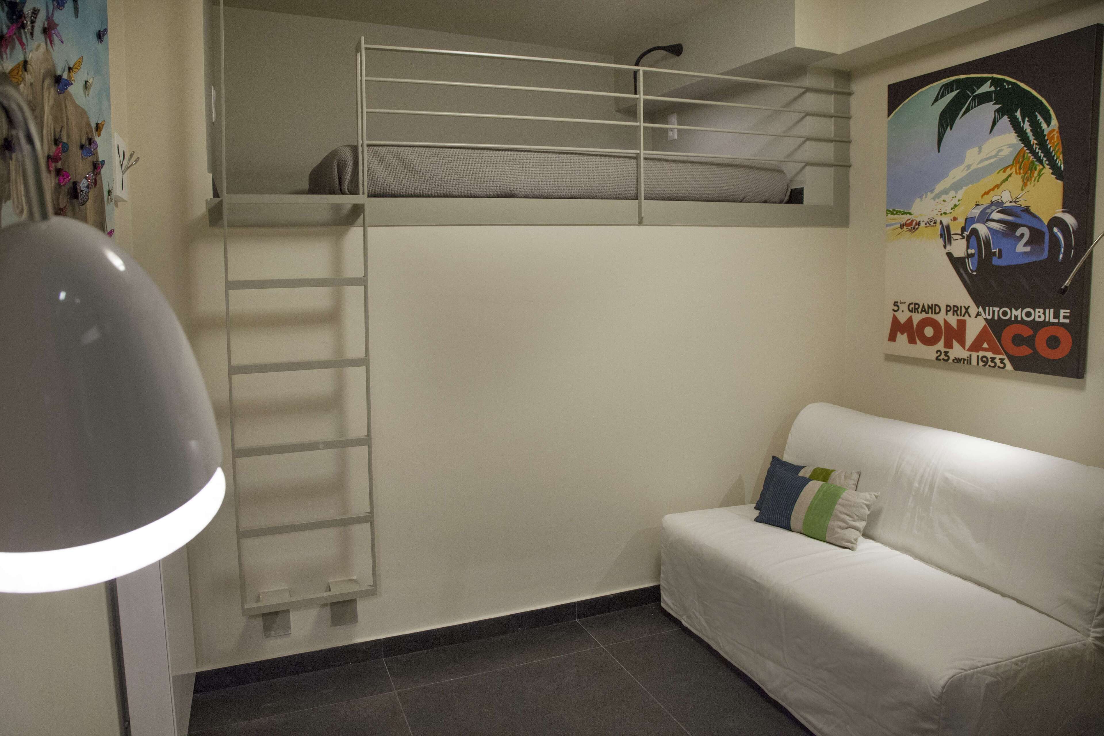 Um quarto com uma cama de solteiro, um sofá branco e um cartaz na parede.