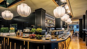 Uma área de bar moderna com balcão curvo, potes de frutas e diversos frascos e copos.