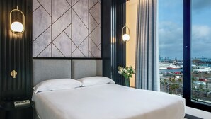 Quarto moderno com uma cama grande, vista para a cidade e design geométrico na parede.
