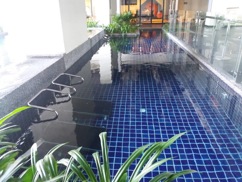 Piscina com azulejos azuis e guarda-corpo de vidro.