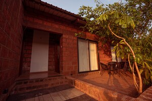 Um edifício de tijolos com um pátio que inclui uma mesa, cadeiras, uma porta e uma janela.