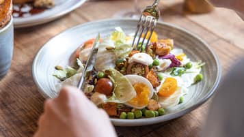 Um prato de comida com vários ingredientes, incluindo folhas verdes, ovos e um molho cremoso.