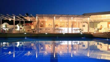 Uma área à beira da piscina com bar e assentos.