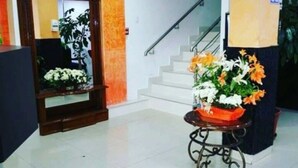 Um hall de entrada com uma mesa de recepção, uma escadaria e um arranjo de flores sobre uma mesa.